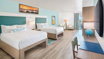 Quarto de hotel com duas camas, uma escrivaninha, televisão e vista para o exterior.