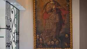 Um quarto com um sofá azul, uma mesa de madeira com um vaso de flores e um quadro grande na parede.