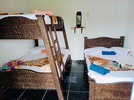 Quarto com duas beliches, uma pequena prateleira com um objeto decorativo e piso ladrilhado.