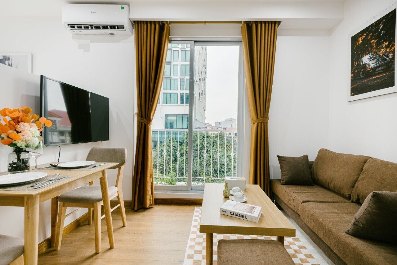 Uma sala de estar moderna com área de jantar, sofá, televisão e janela com cortinas.