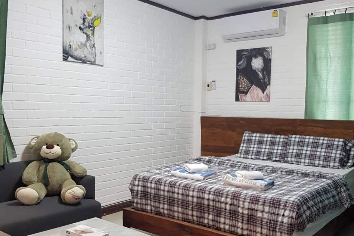 Quarto com cama, cadeira, mesa e um ursinho de pelúcia.