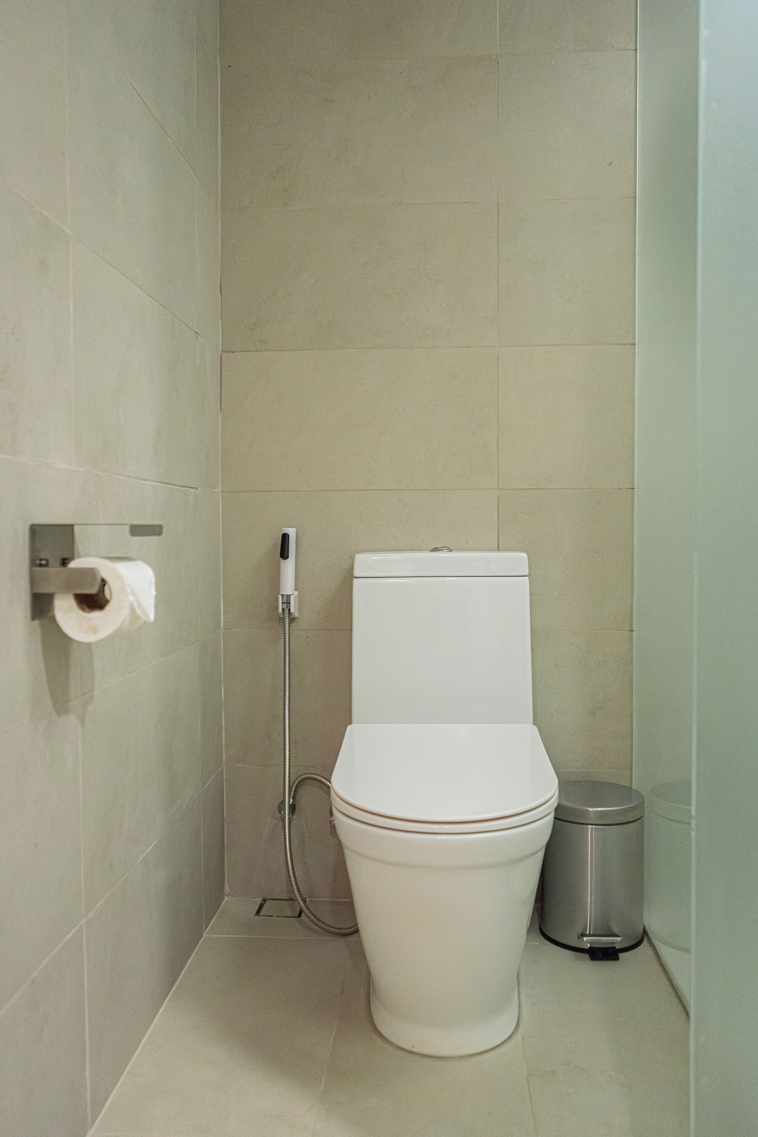 Um banheiro pequeno e moderno, com vaso sanitário, lixeira e suporte para toalhas de papel.