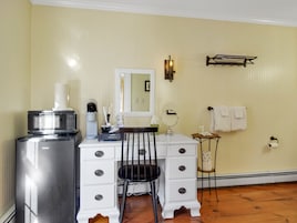 Casa de banho com lavatório, espelho, porta-toalhas e máquina de café.