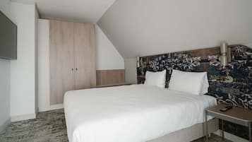 Quarto com cama, mesa de cabeceira, televisão e guarda-roupa.