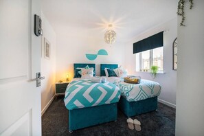 Quarto com duas camas, uma mesa de cabeceira, uma luminária, uma luz em forma de globo e uma janela com vista.