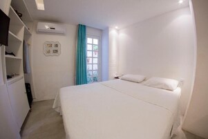 Quarto com uma cama de solteiro, guarda-roupa, janela com cortinas e ar condicionado.