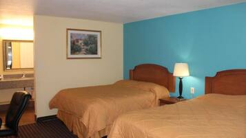 Quarto de hotel com duas camas, uma escrivaninha, uma cadeira, um abajur e um quadro na parede.