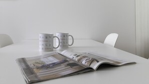 Duas canecas brancas com logotipos da Italianway sobre uma mesa branca com uma revista aberta.