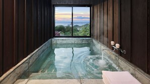 Uma banheira de hidromassagem retangular com vista para o pôr do sol e montanhas.