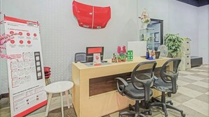 Uma área de recepção com balcão, duas cadeiras, quadro branco e mural de avisos.