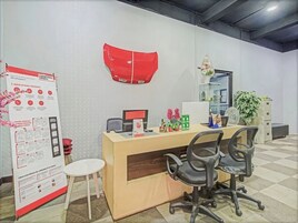 Uma área de recepção com balcão, duas cadeiras, quadro branco e mural de avisos.