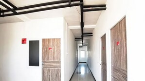 Corredor com portas de madeira, um detector de incêndio e piso limpo.