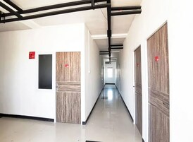 Corredor com portas de madeira, um detector de incêndio e piso limpo.