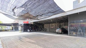 Uma área de estacionamento coberta com piso de tijolos, um carro e uma motocicleta.