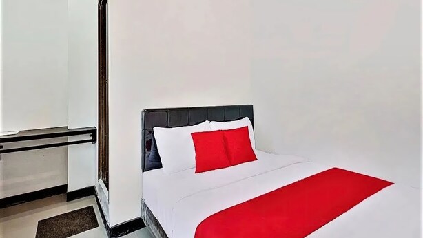 Quarto de hotel com cama, mesa de cabeceira, espelho e ar condicionado.