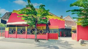 Um edifício com fachada vermelha e amarela, portão e uma árvore na frente.