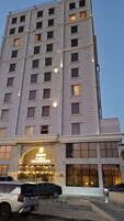 Hotel com vários andares, fachada moderna, grandes janelas e entrada destacada com sinalização iluminada.