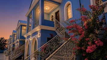 Uma fileira de edifícios azuis com janelas em arco e uma escadaria com grades de metal ornamentadas.