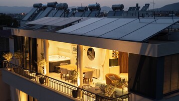 Um edifício moderno com telhado plano, painéis solares e varanda com plantas em vasos.
