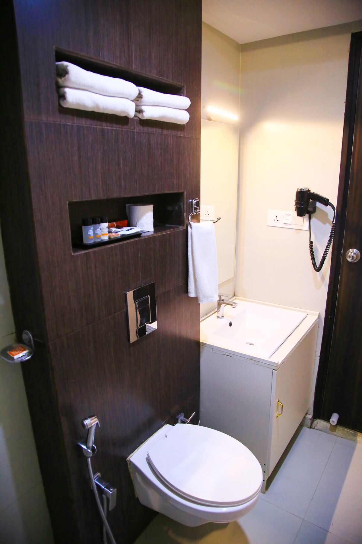 Uma casa de banho compacta com sanita, lavatório e porta-toalhas.