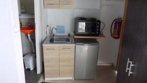Cozinha compacta com micro-ondas, pia e pequena geladeira.