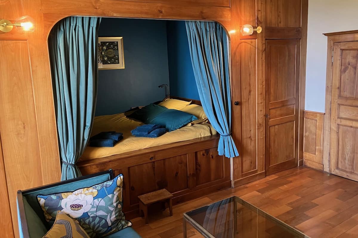 Um quarto acolhedor com uma cama, paredes de madeira, uma mesinha e um armário.