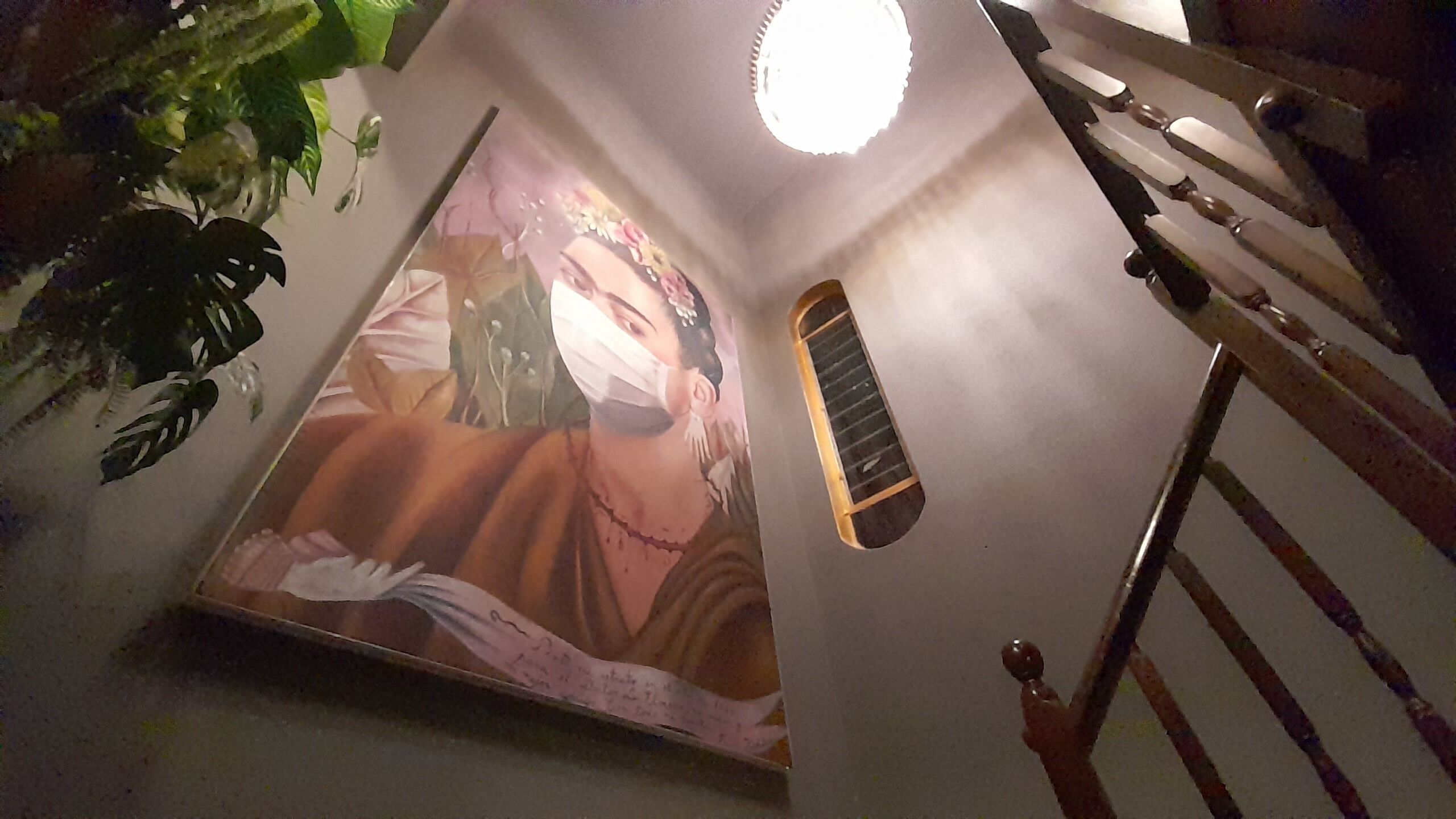 Quarto com um grande mural, escada e planta em vaso.