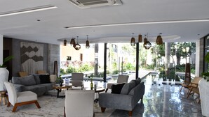 Amplo espaço interno com assentos, uma grande janela e vista para um jardim.