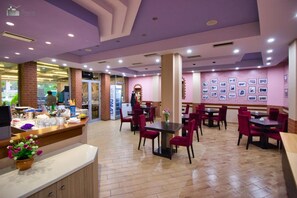 Um restaurante com balcão, cadeiras vermelhas e uma parede decorada com quadros.