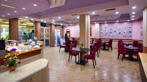 Um restaurante com balcão, cadeiras vermelhas e uma parede decorada com quadros.