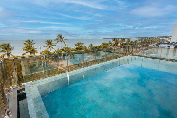Piscina infinita no terraço, com vista clara para a praia e o oceano.
