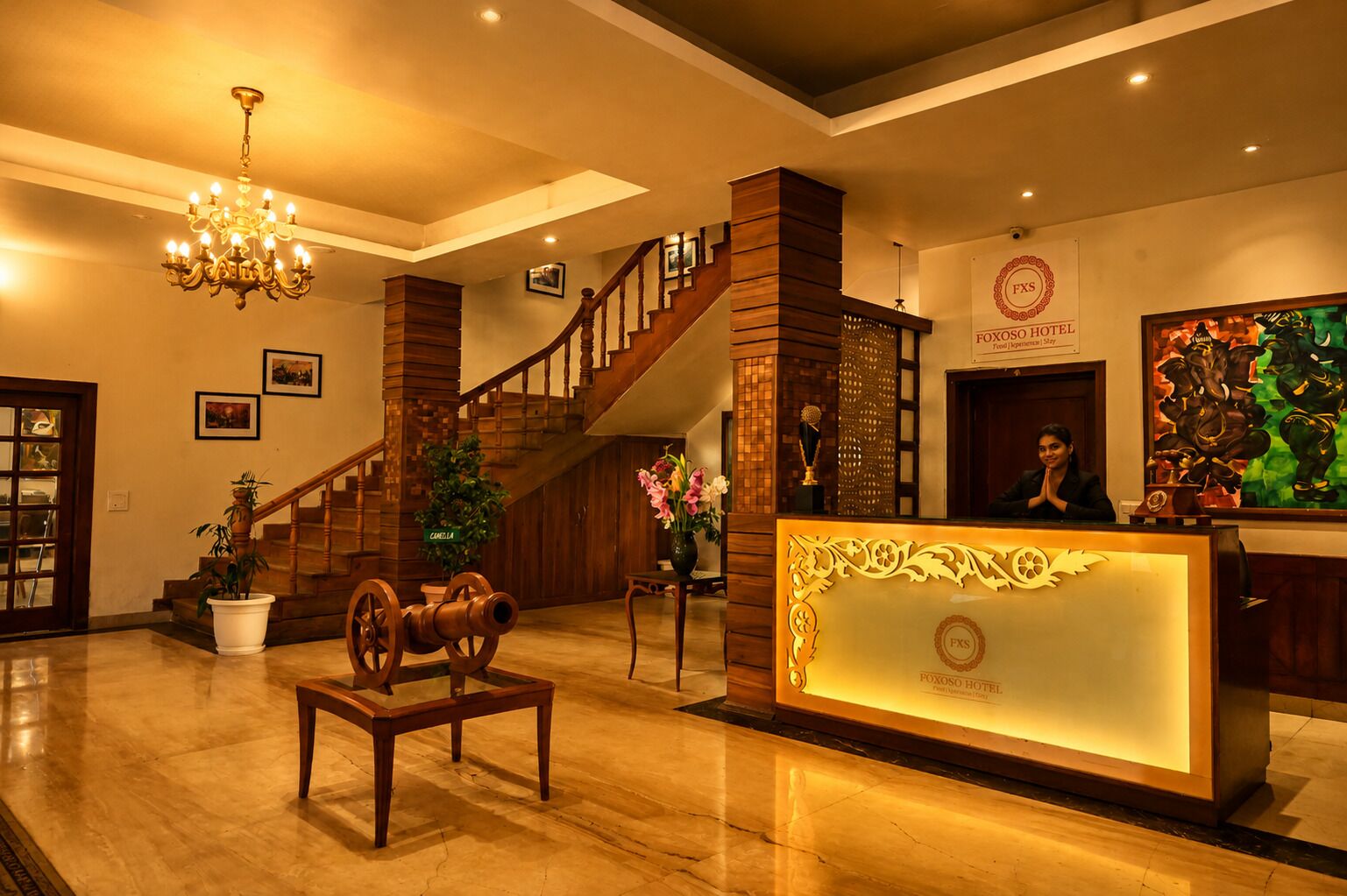 Um hall de hotel com uma escadaria imponente, uma receção e um candelabro.