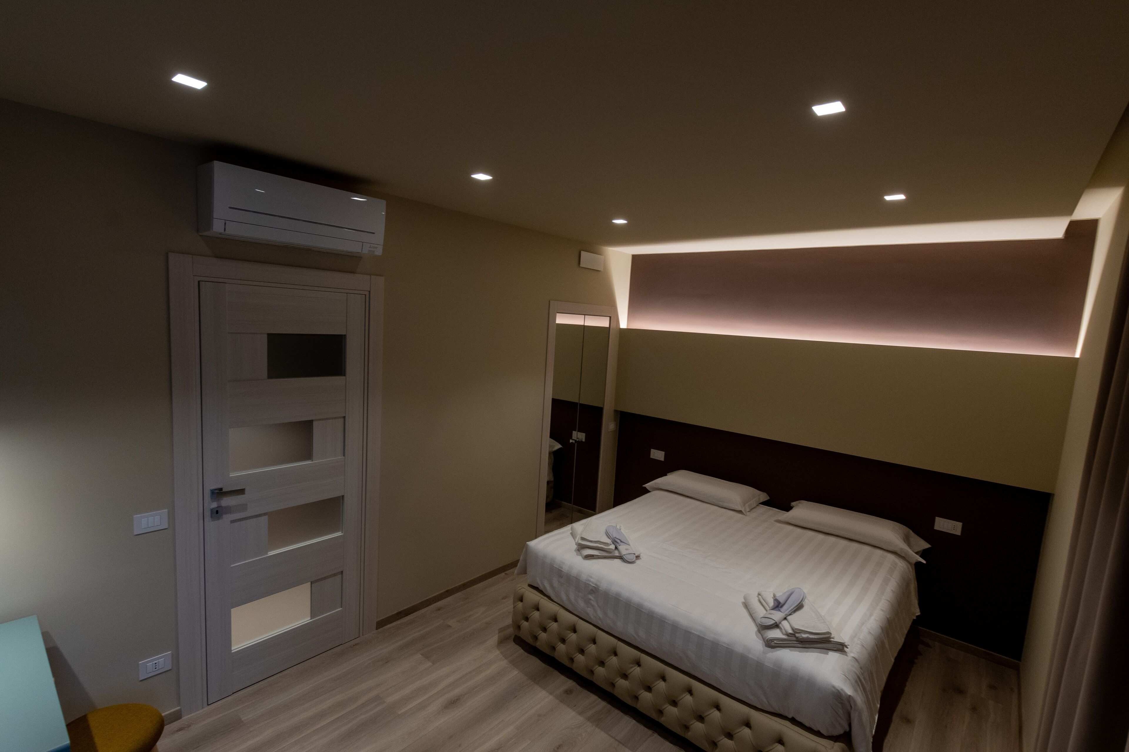 Quarto de hotel moderno com uma cama, um guarda-roupa e ar-condicionado instalado no teto.