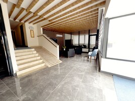 Um hall amplo com escada, balcão de recepção e área de estar.