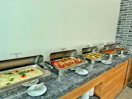Buffet com diversos pratos, incluindo arroz, vegetais e carnes.