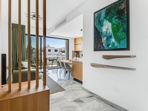 Um interior moderno com área de refeições, cozinha e vista através de grandes janelas.