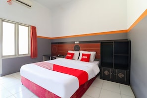 Quarto de hotel com uma cama grande, um guarda-roupa e uma janela com cortinas.