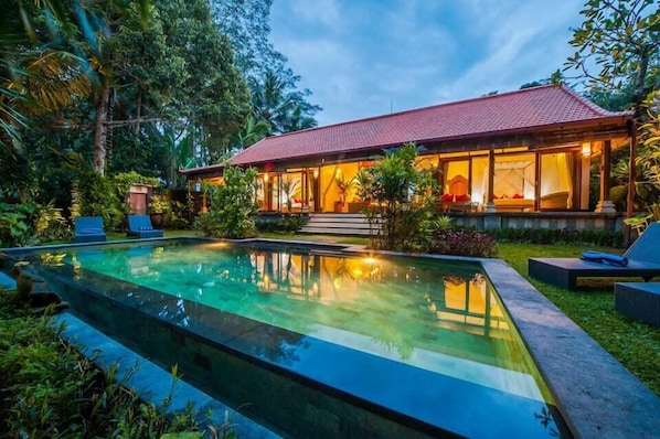 Uma casa moderna com piscina, rodeada por vegetação exuberante.