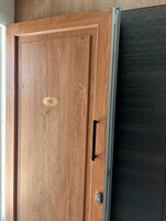 Uma porta de madeira com uma placa de identificação com o número 102 e um puxador preto.