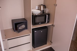 Uma cozinha compacta equipada com micro-ondas, mini-geladeira e cofre.