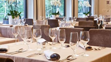 Um restaurante com várias mesas preparadas para refeições, cada uma com copos de vinho, talheres e guardanapos.