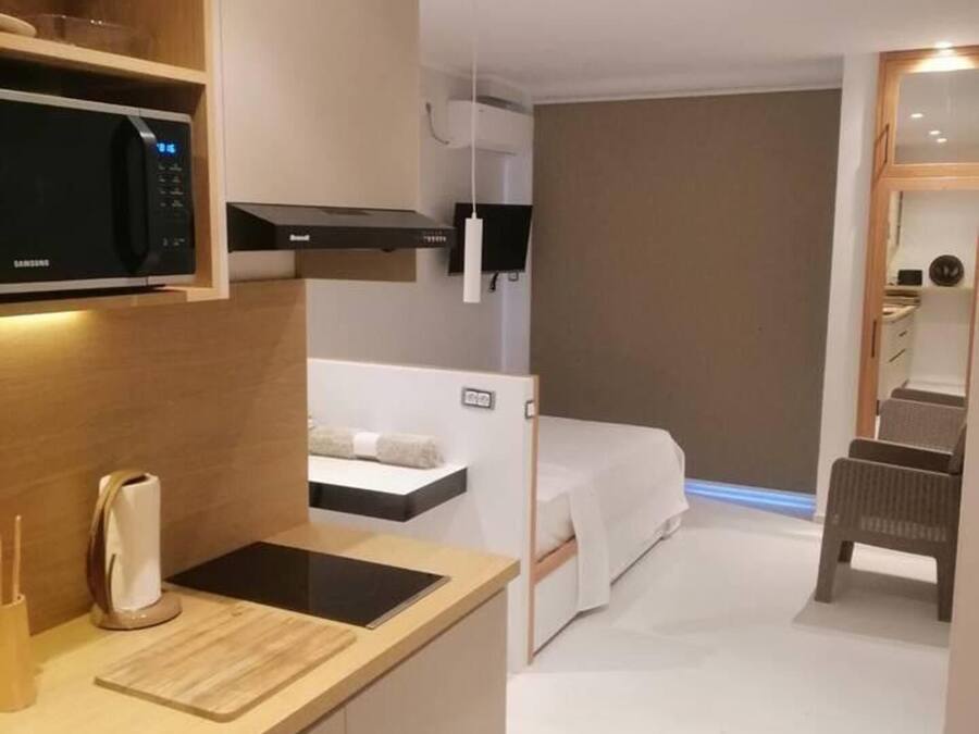 Quarto de hotel moderno com cozinha compacta, cama e área de estar.