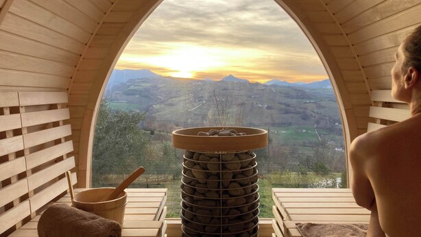 Interior de madeira com uma grande janela em arco com vista para uma paisagem deslumbrante ao pôr do sol.