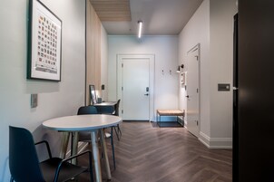 Quarto moderno com uma mesa redonda, cadeiras, um banco, uma porta e um quadro na parede.