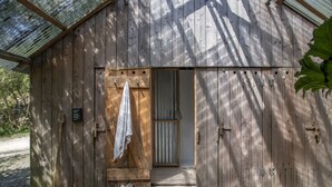 Um edifício rústico de madeira com uma porta grande, um pequeno degrau que leva à entrada e uma toalha pendurada na porta.