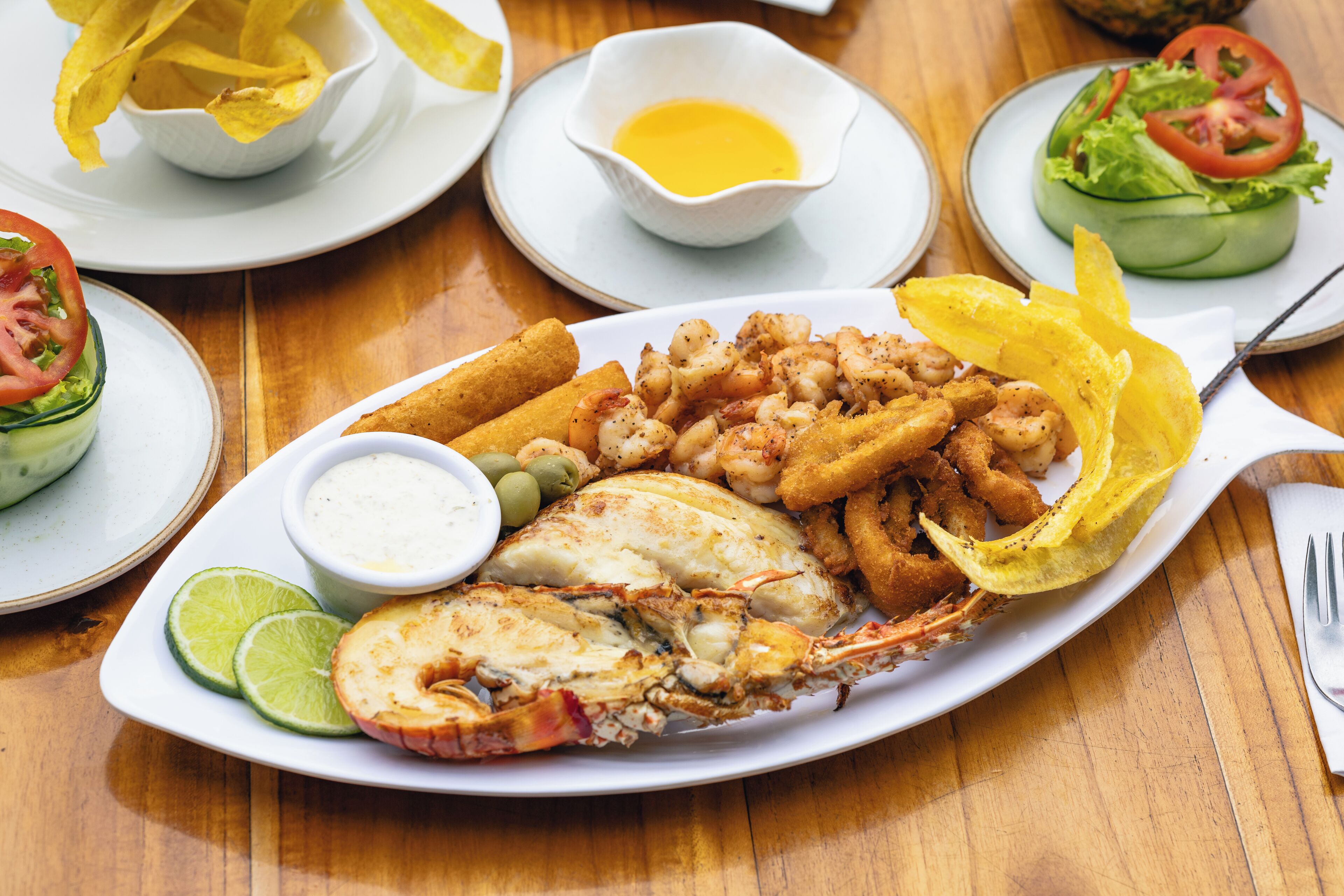 Prato de frutos do mar com camarões, pernas de caranguejo e batatas fritas sobre uma mesa de madeira.