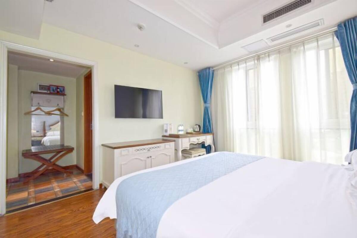 Quarto de hotel com uma cama grande, televisão de tela plana, cômoda, escrivaninha e closet espaçoso.