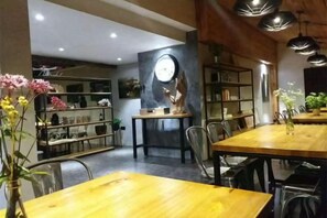 Uma sala de jantar com mesa e cadeiras de madeira, cercada por estantes com livros e objetos decorativos.
