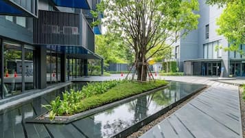 Um edifício moderno com um espelho d'água e vegetação.