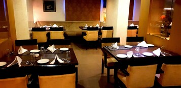 Um restaurante com várias mesas preparadas para refeições, cada uma com pratos, talheres e guardanapos.